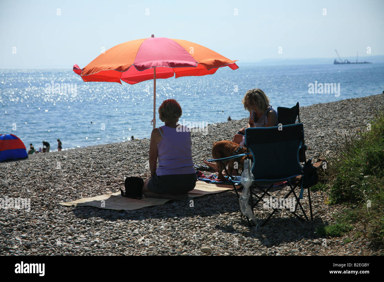 Two people sitting under a sun umbrella Stock Photo - Alamy