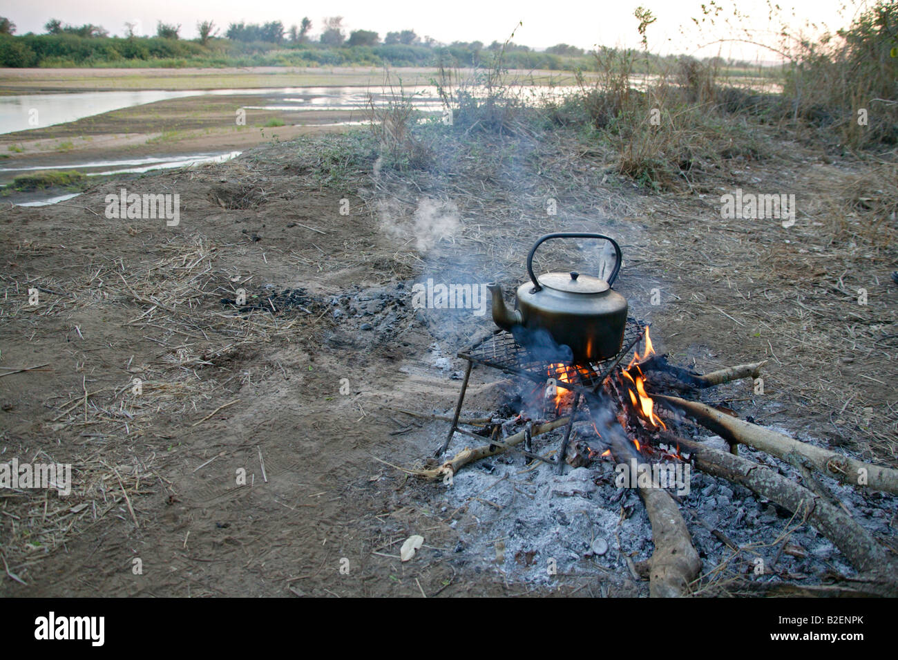 A kettle on a log fire in a camp site located on the banks of a wild ...