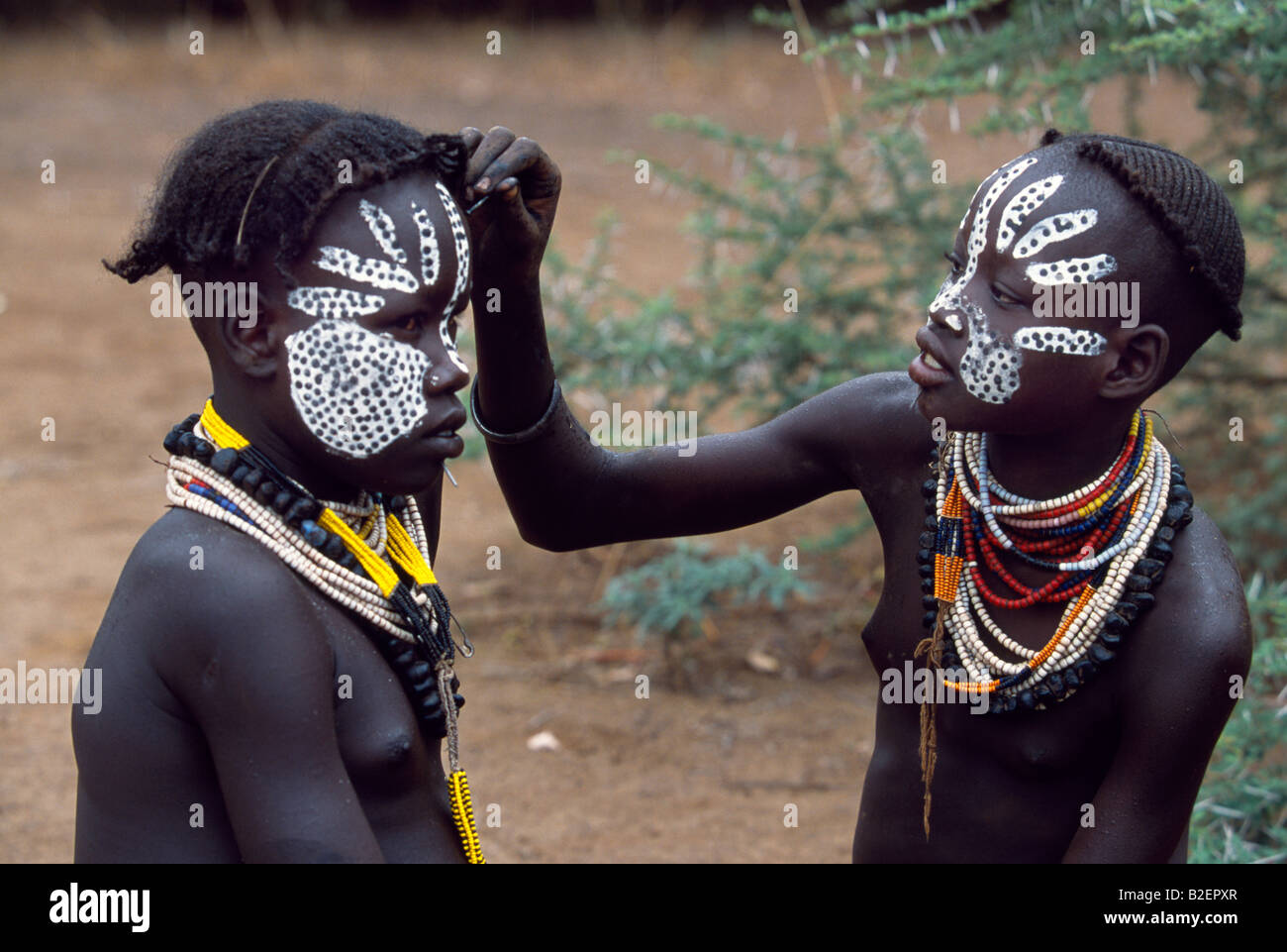 A young Karo girl decorates her friends face. A small Omotic tribe ...