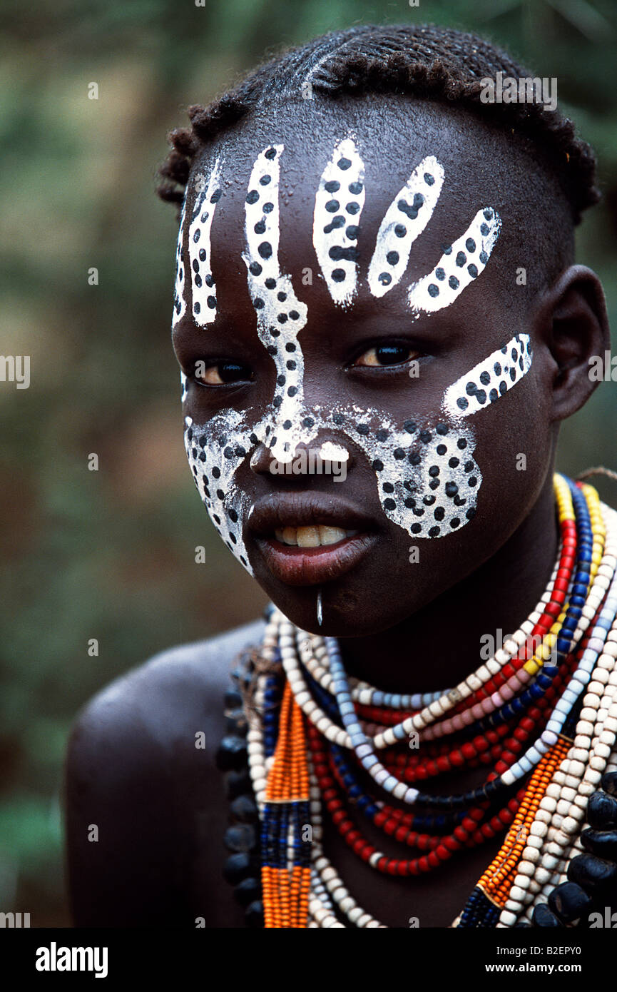 A young Karo girl has decorated herself with face paint, an intricate ...