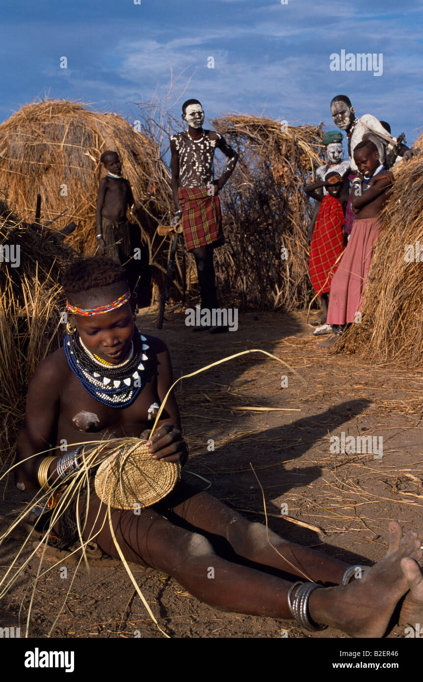A Nyangatom girl weaves a grass basket. The Nyangatom or Bume are a ...