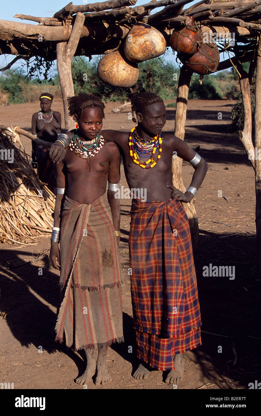 Two Dassanech girls stand beside a raised storage platform at a ...