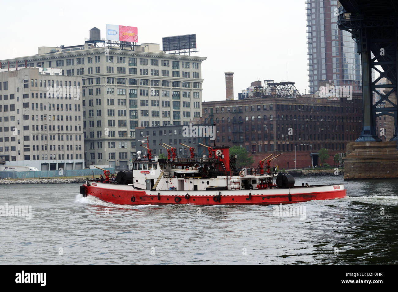 A fireboat on the East River in New York City passes under the ...