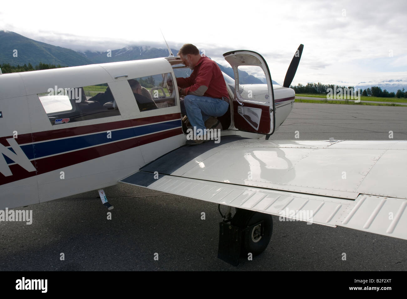 Pilot helping tourist to board smal aircraft for flight seeing trip ...
