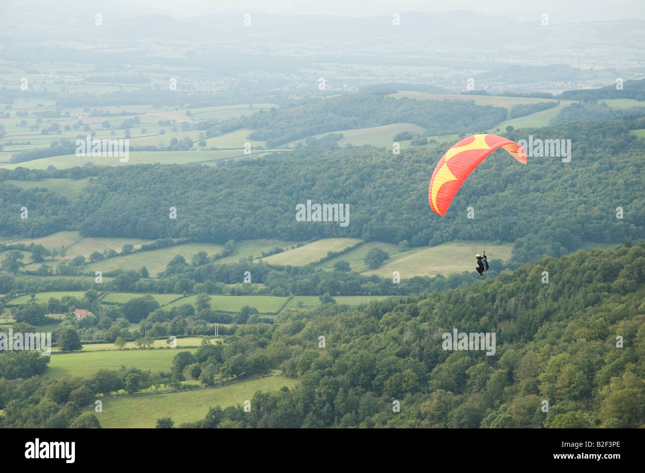 Paraglider flying high above green scenery Stock Photo - Alamy