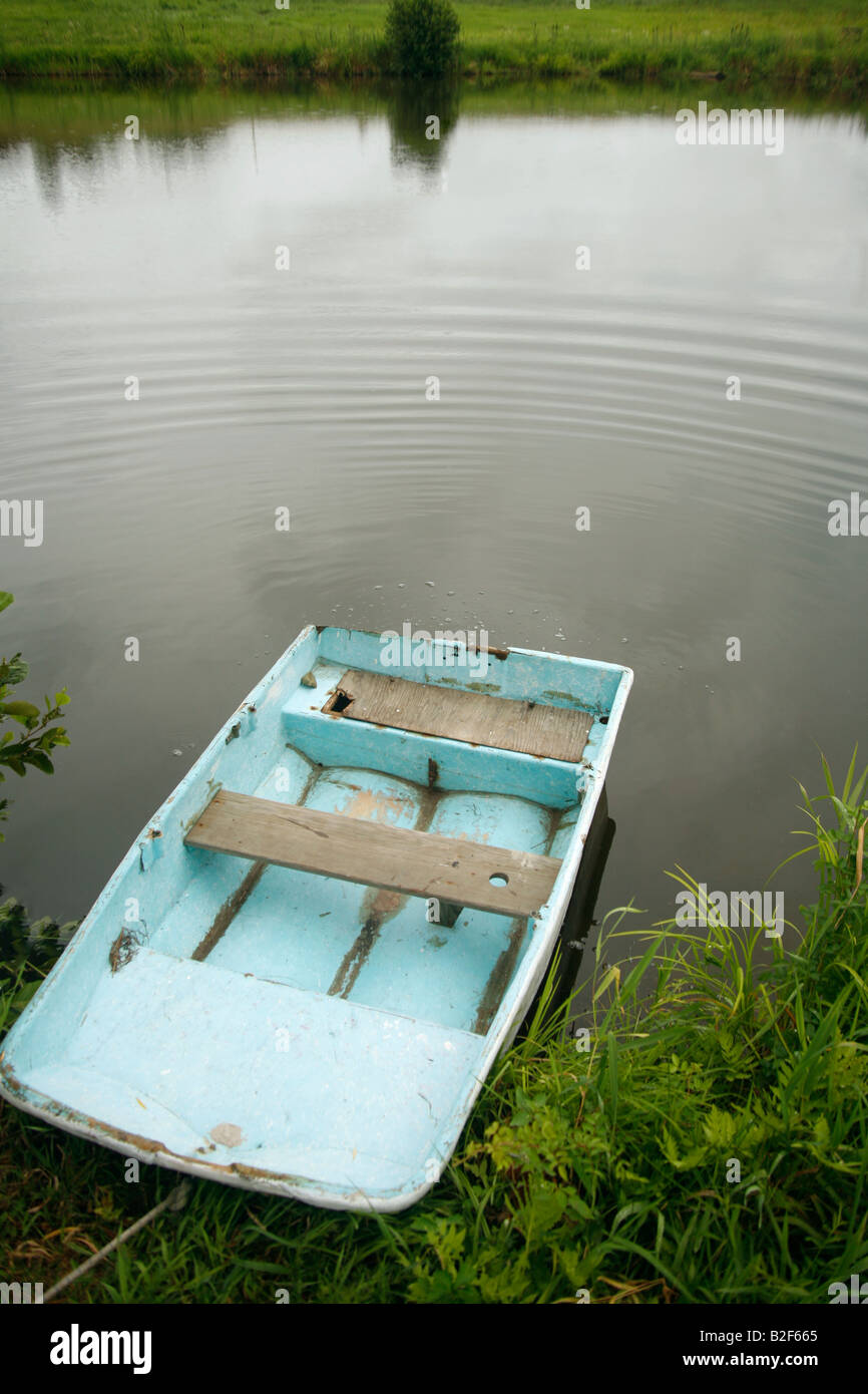 Mint blue rustic wooden row boat on a pond with green grass landscape ...