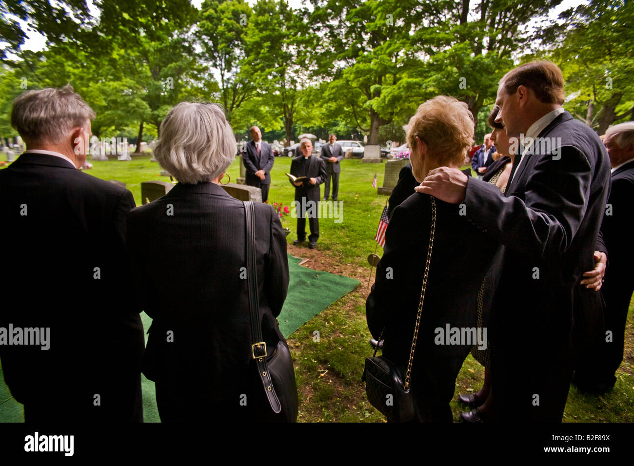 A priest officiates at a burial at a Catholic cemetary in Stoneham MA ...