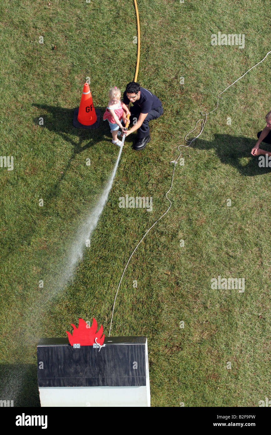 A young girl using the water hose to put out the fire on the display ...