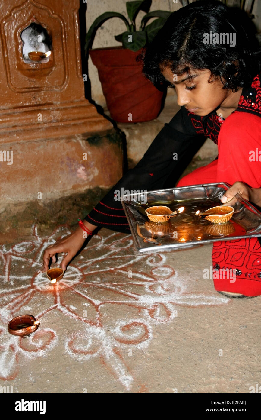 Young Hindu girl placing divas on a rangoli on the occasion of Diwali ...