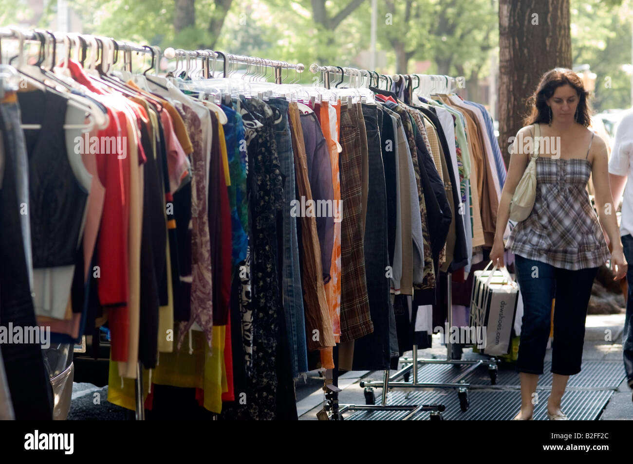 Woman walks past racks of clothing at a stoop sale in the trendy ...