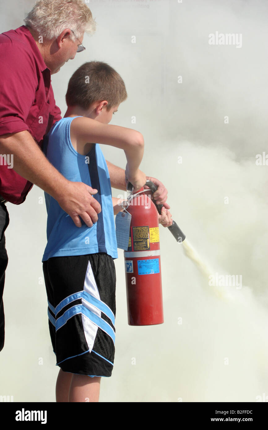 A man showing a child how to use a fire extinguisher to extinguish a ...