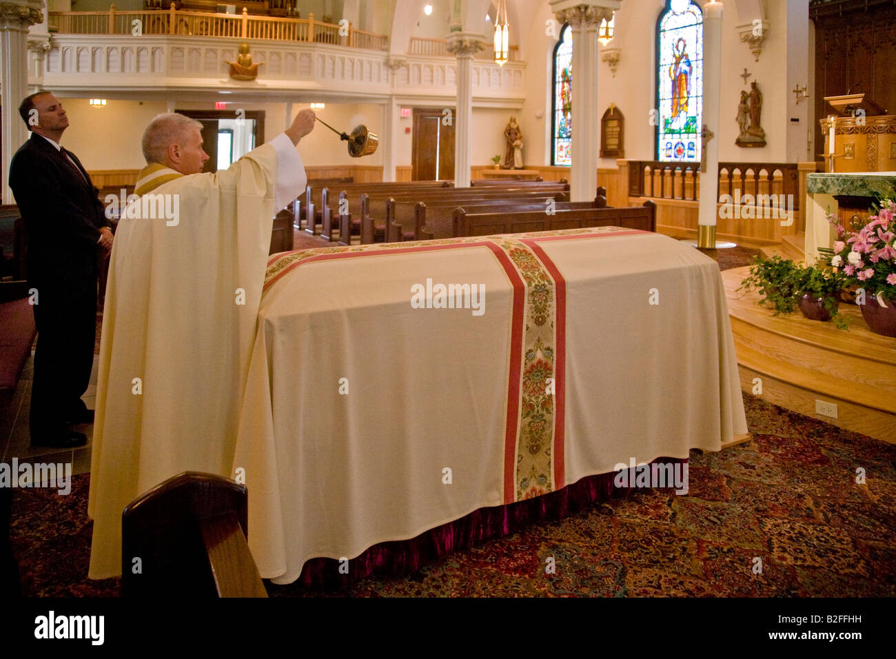 A Priest Waves A Senser Over The Casket At A Catholic Funeral Mass In