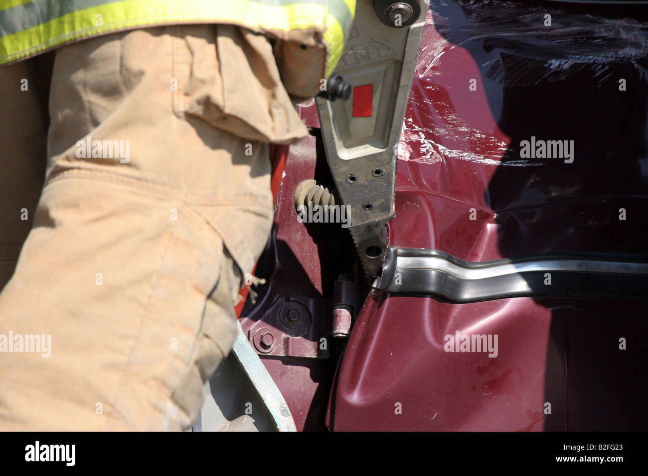 A firefighter using a TNT extrication tool to pry the door off a car in ...