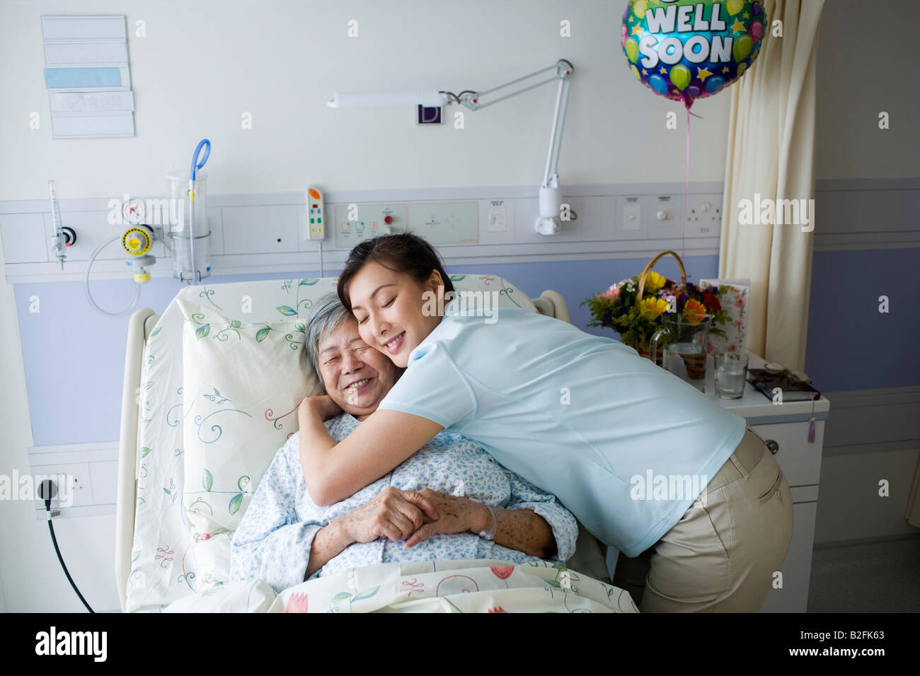 Mid adult woman hugging a female patient and smiling Stock Photo - Alamy
