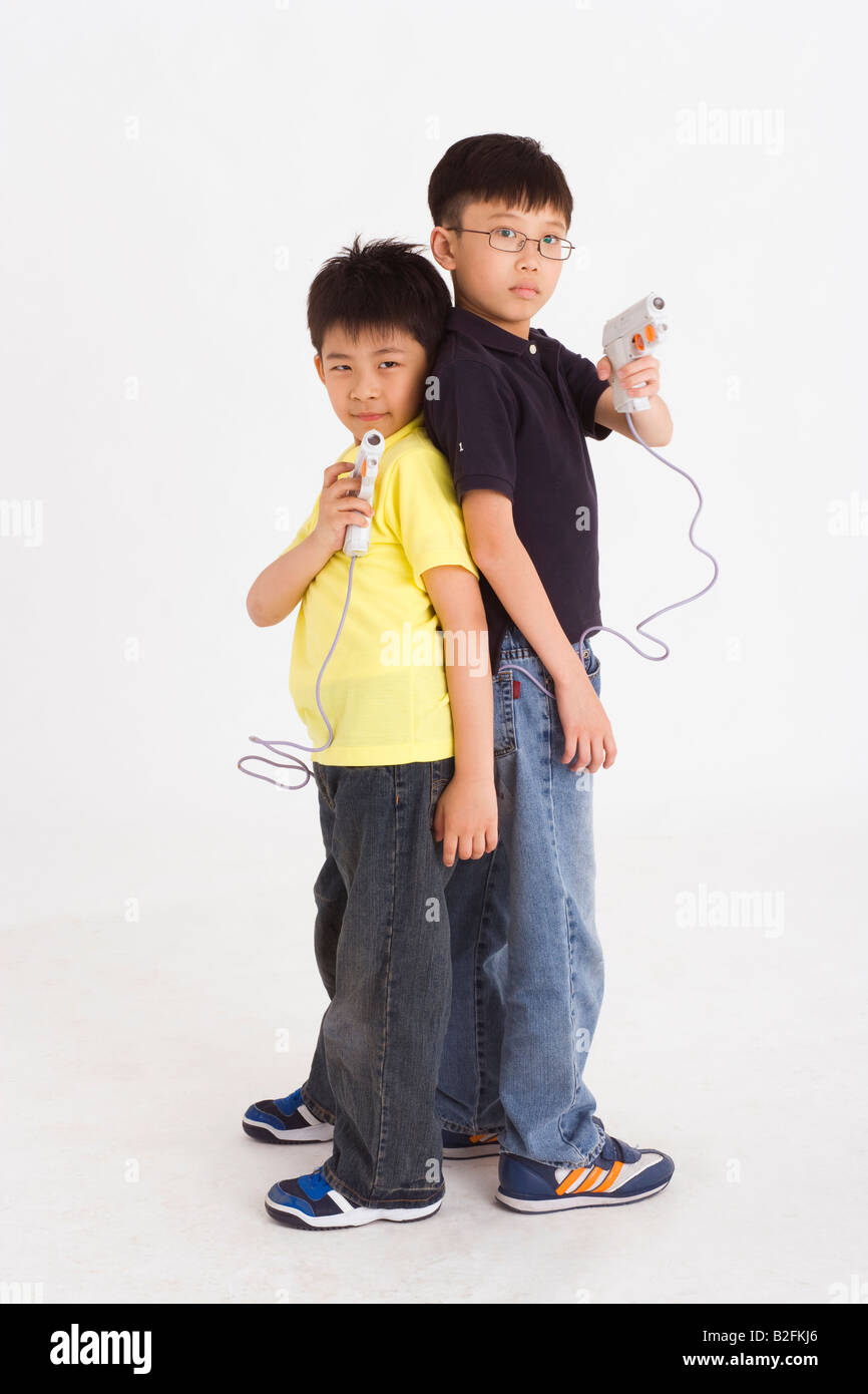 Side profile of two boys standing back to back and holding video game ...