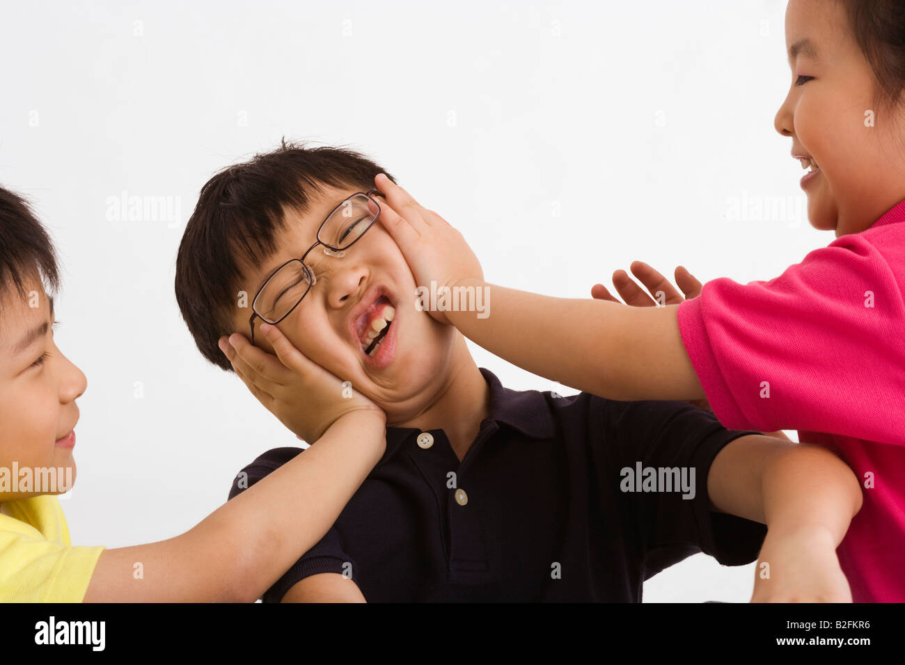 Two children pushing a boy's mouth Stock Photo - Alamy
