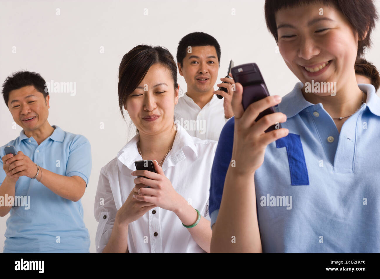 Five people text messaging and smiling Stock Photo - Alamy