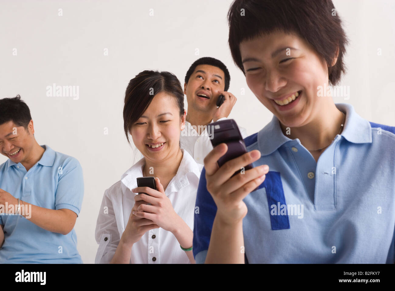 Four people using mobile phones and smiling Stock Photo - Alamy