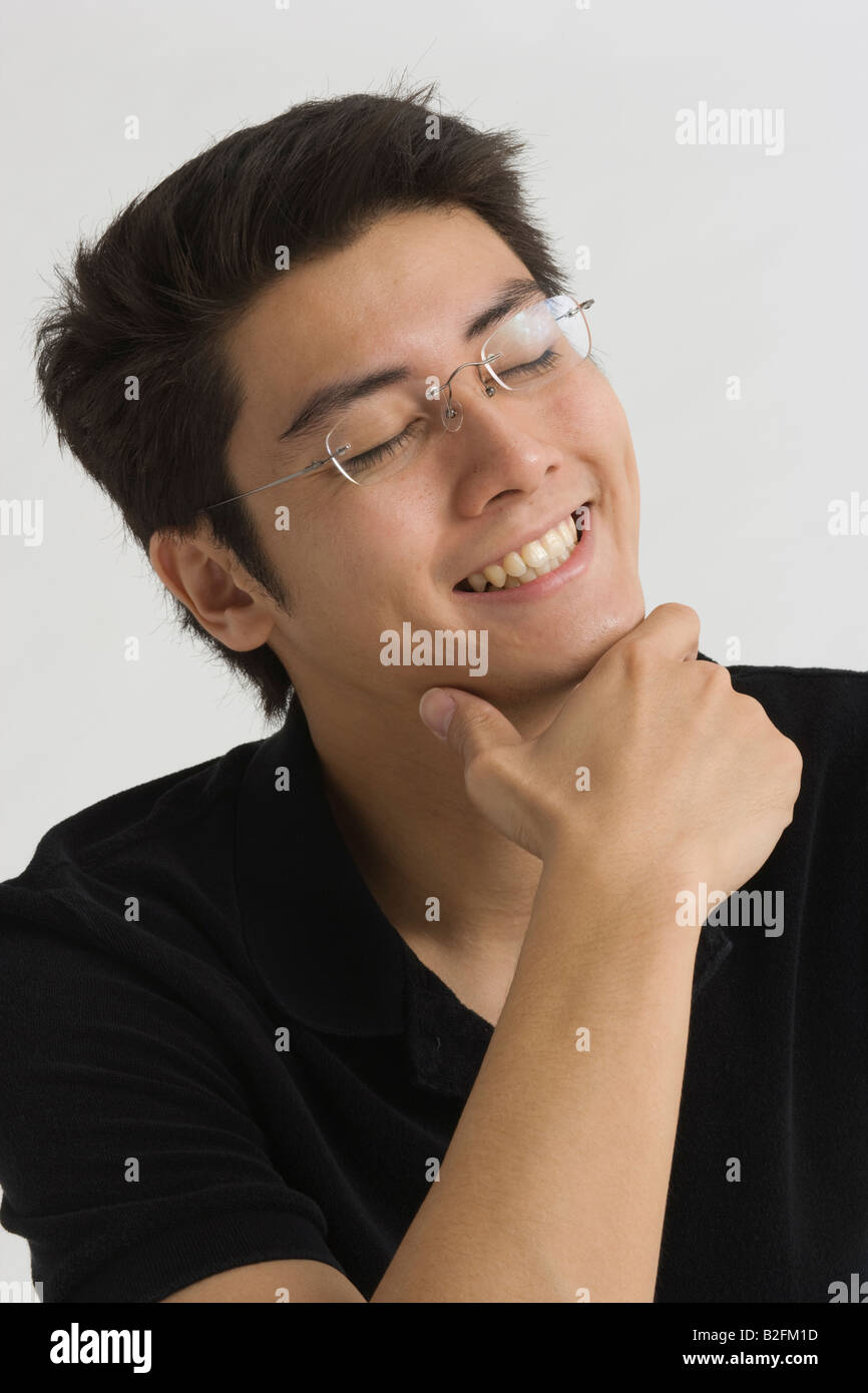 Close-up of a young man thinking and smiling Stock Photo - Alamy
