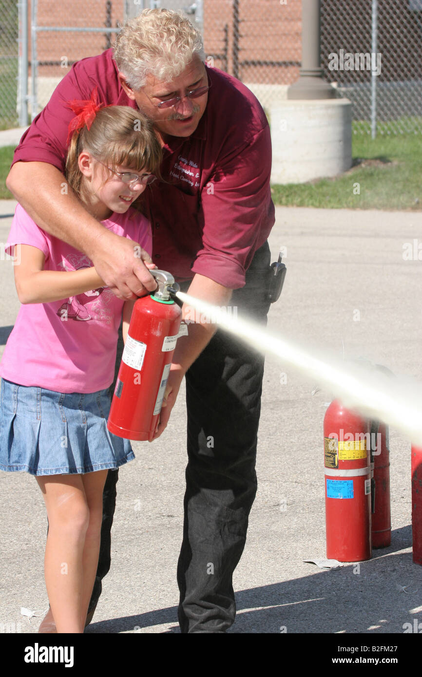 A man showing a child how to use a fire extinguisher to extinguish a ...