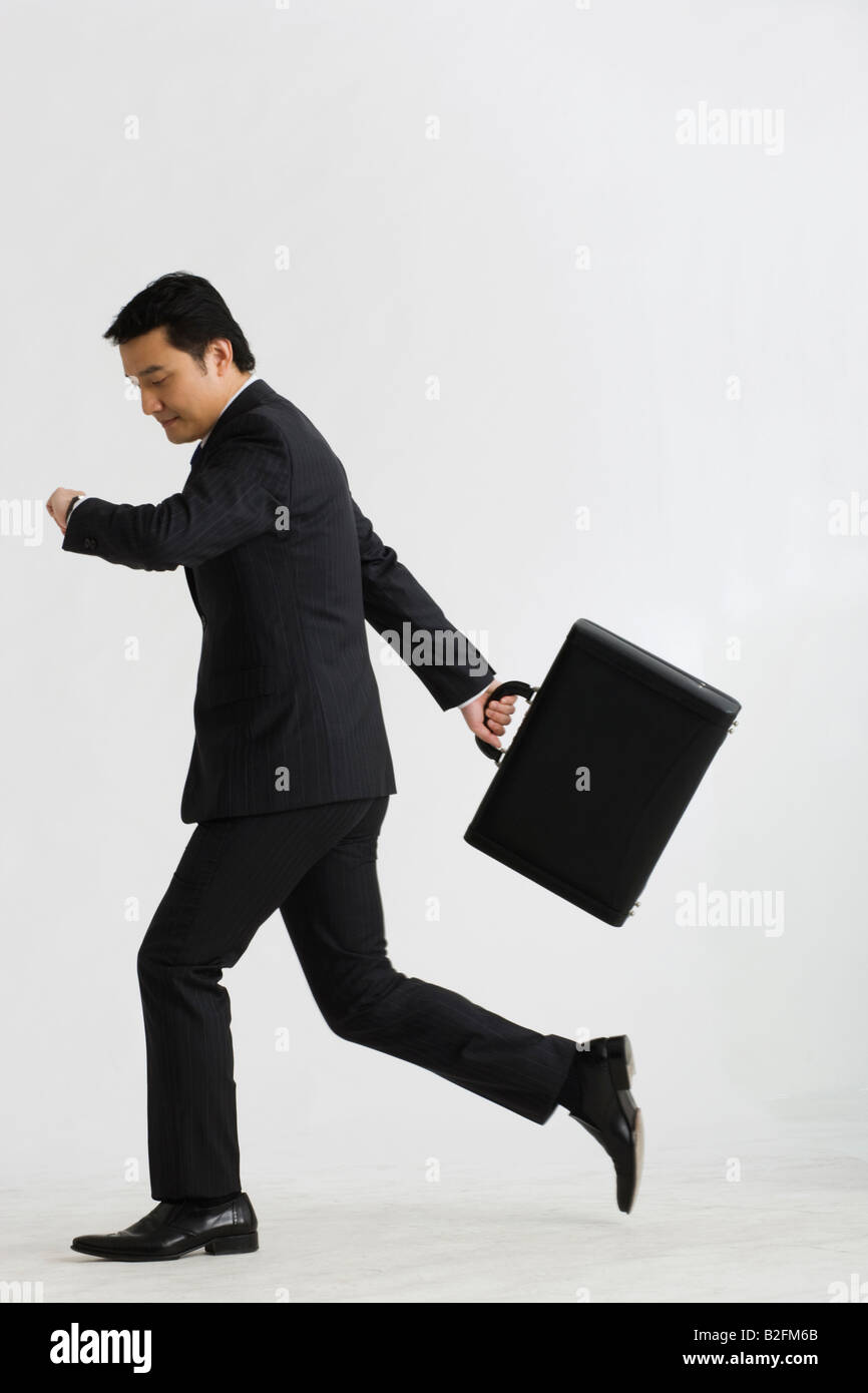 Side profile of a businessman carrying a briefcase and checking the ...