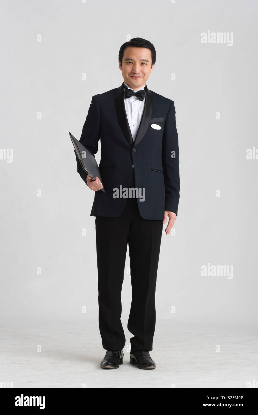 Portrait of a waiter holding a menu and standing Stock Photo - Alamy