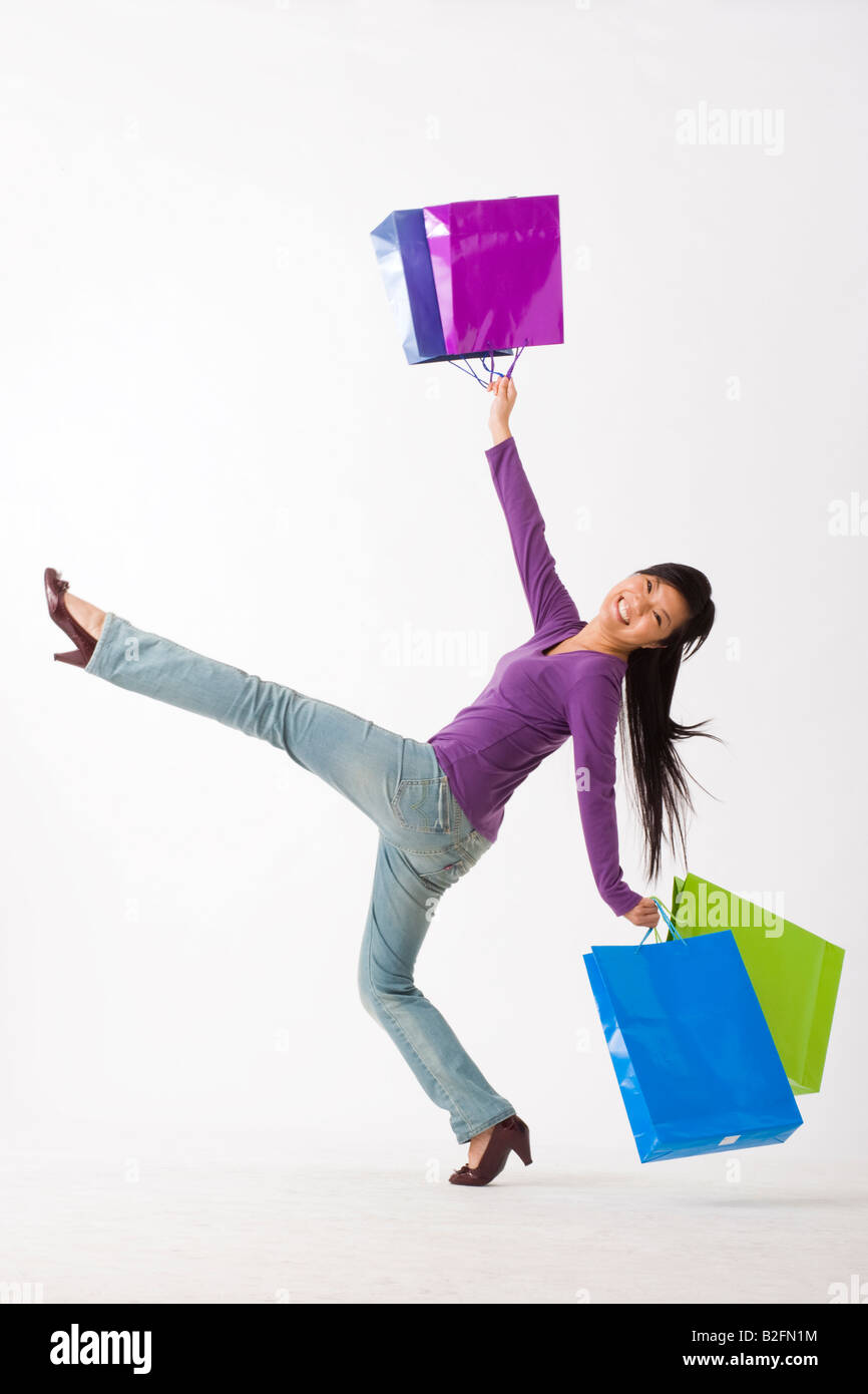 Portrait of a young woman carrying shopping bags and standing on her ...