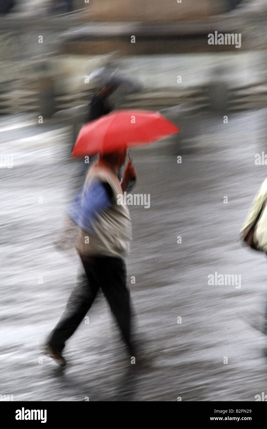 man with umbrella running in heavy rain in town Stock Photo - Alamy