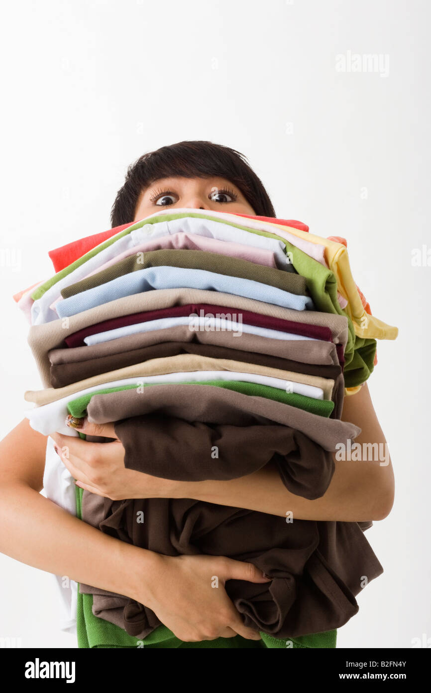 Portrait of a young woman holding a stack of clothes Stock Photo - Alamy