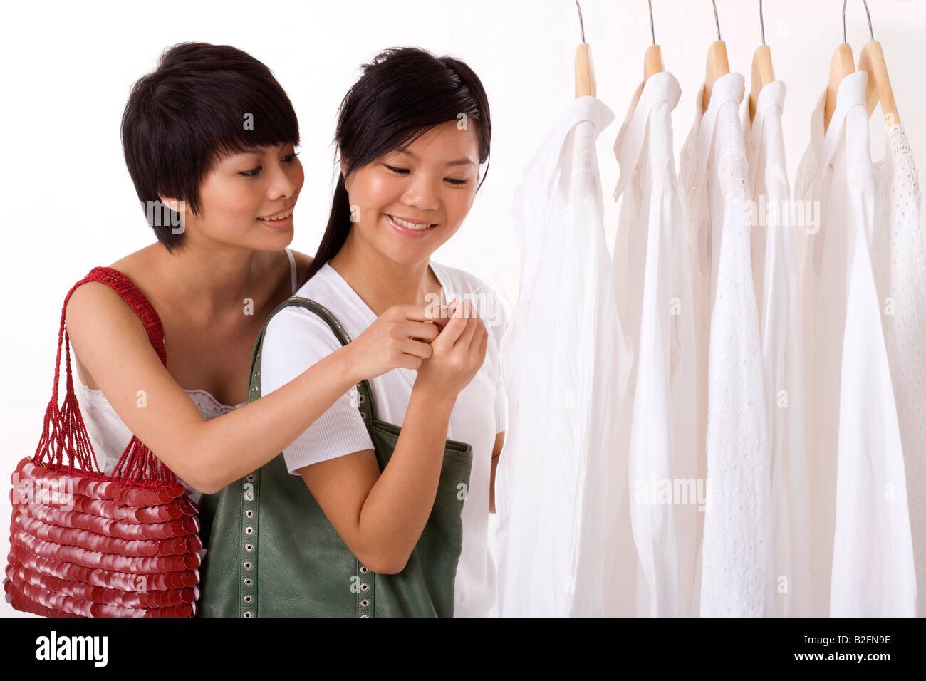 Two young women looking at the price tag of a dress in a clothing store ...