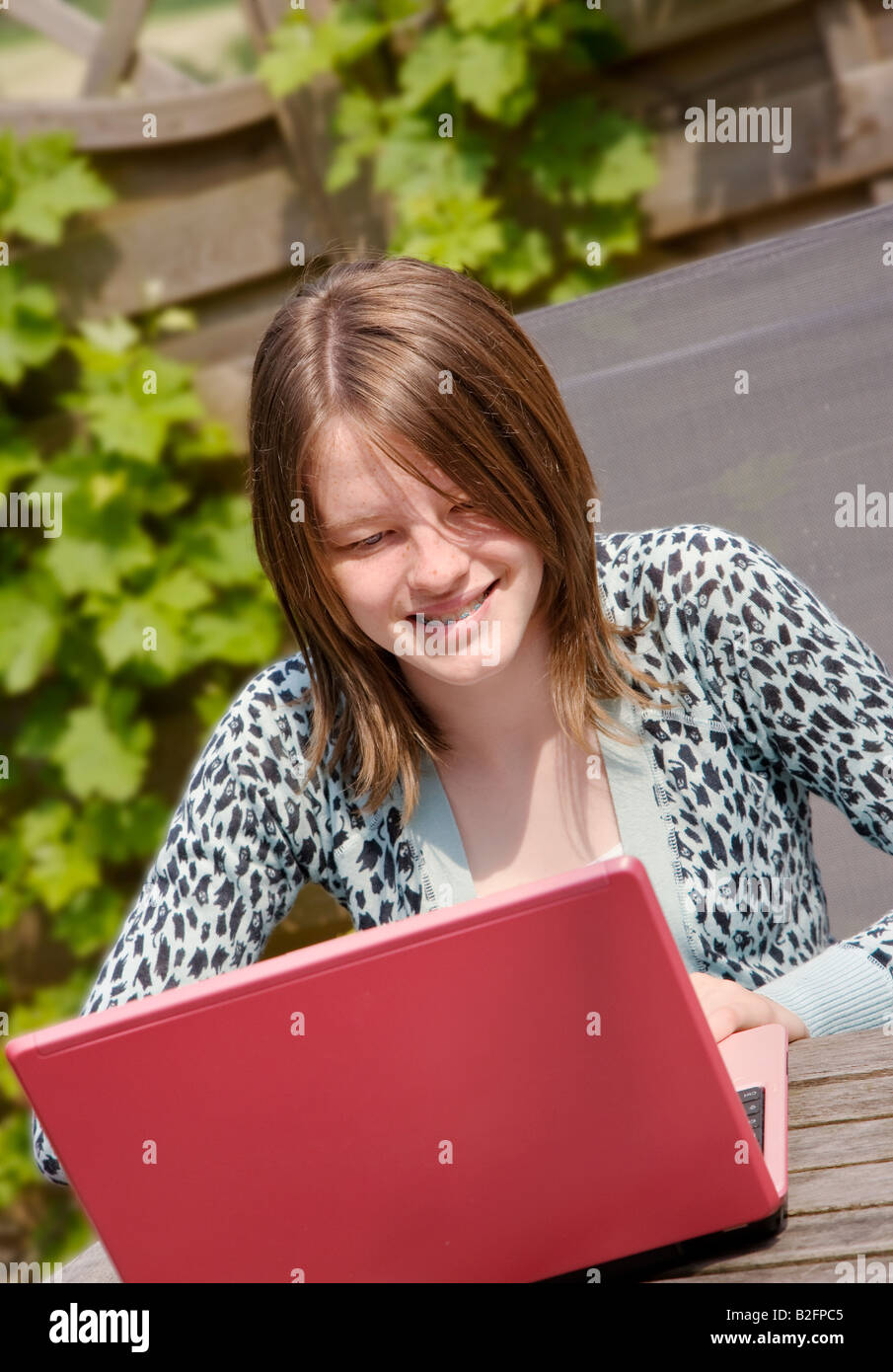 YOUNG GIRL WITH BRACE ON HER TEETH USING A LAPTOP COMPUTER IN GARDEN UK ...