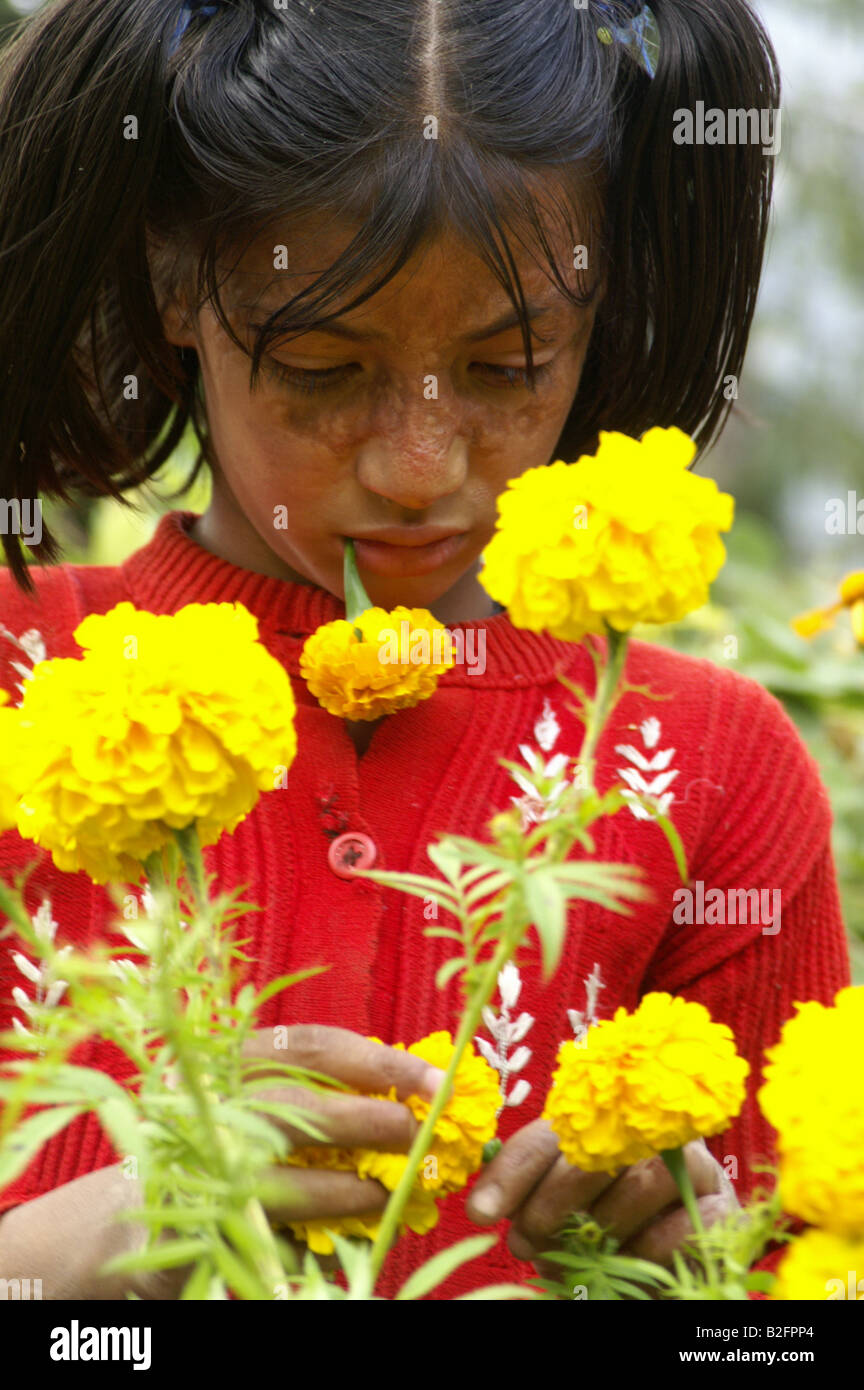 One indian girl young with yellow flower in her mouth in garden playing ...