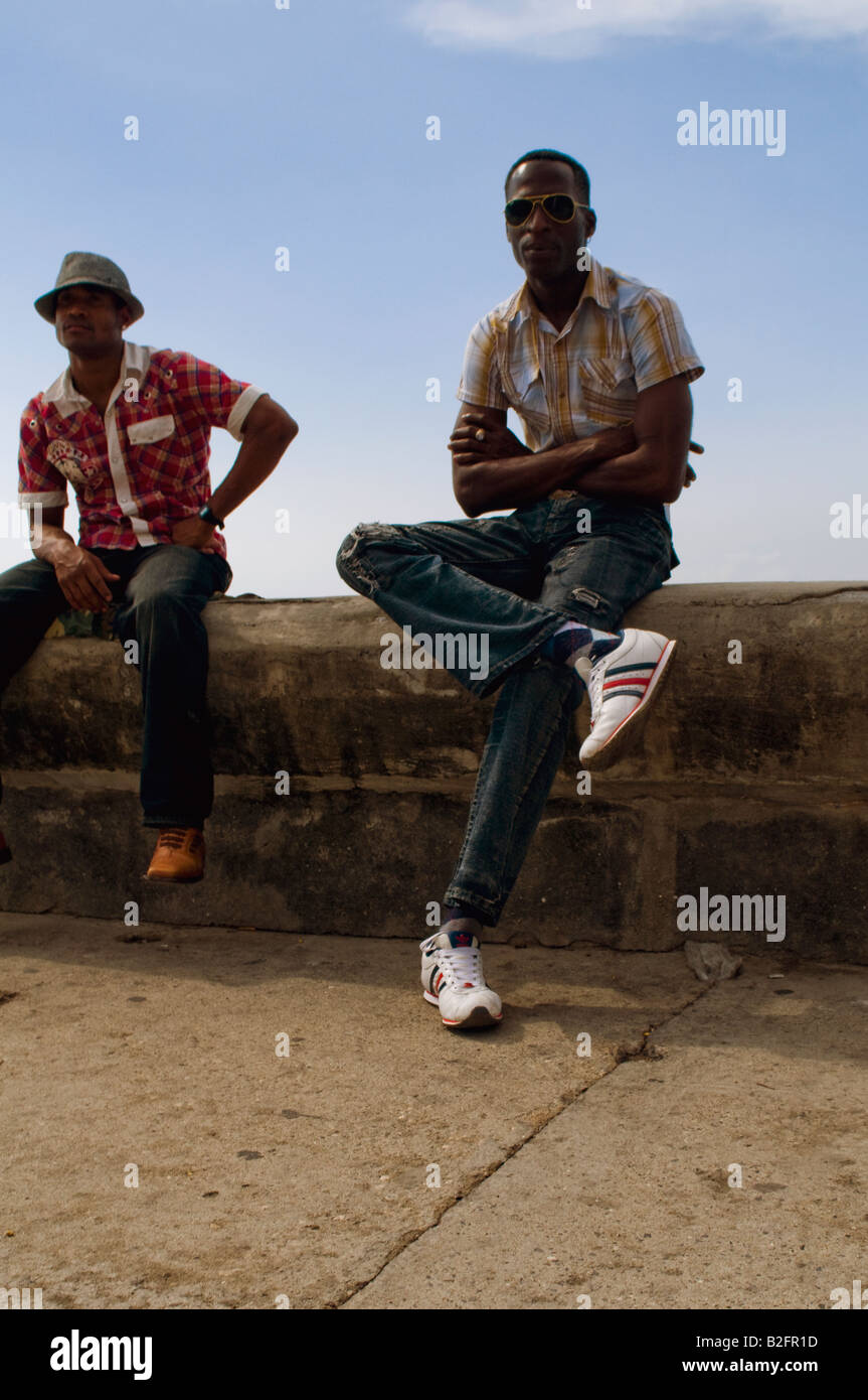 local cuban men sit on the wall of the Malecon in Havana cuba Stock ...