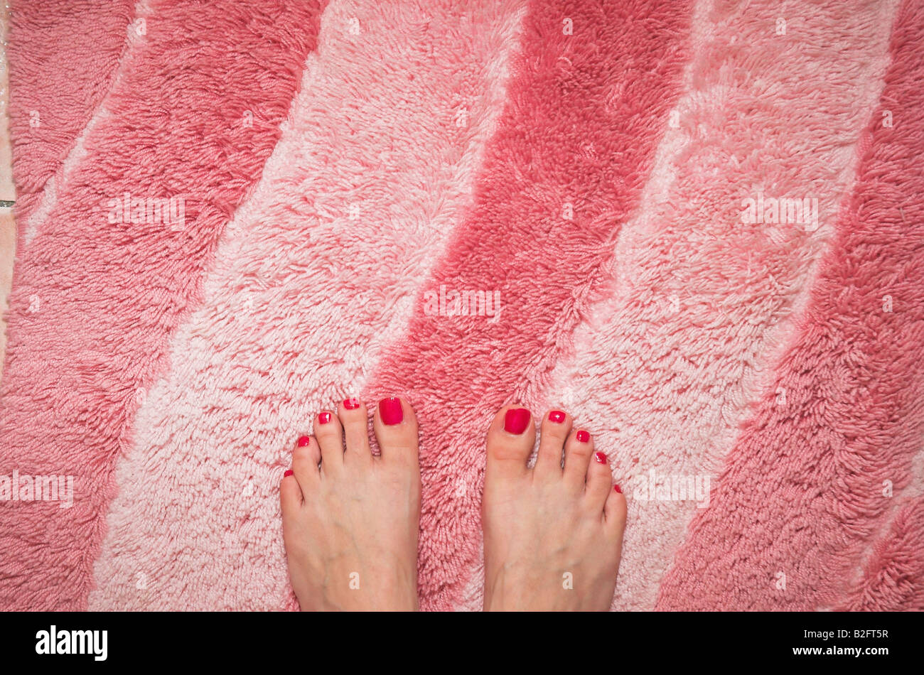 Young woman with red painted toes standing on bathrom rug Stock Photo ...