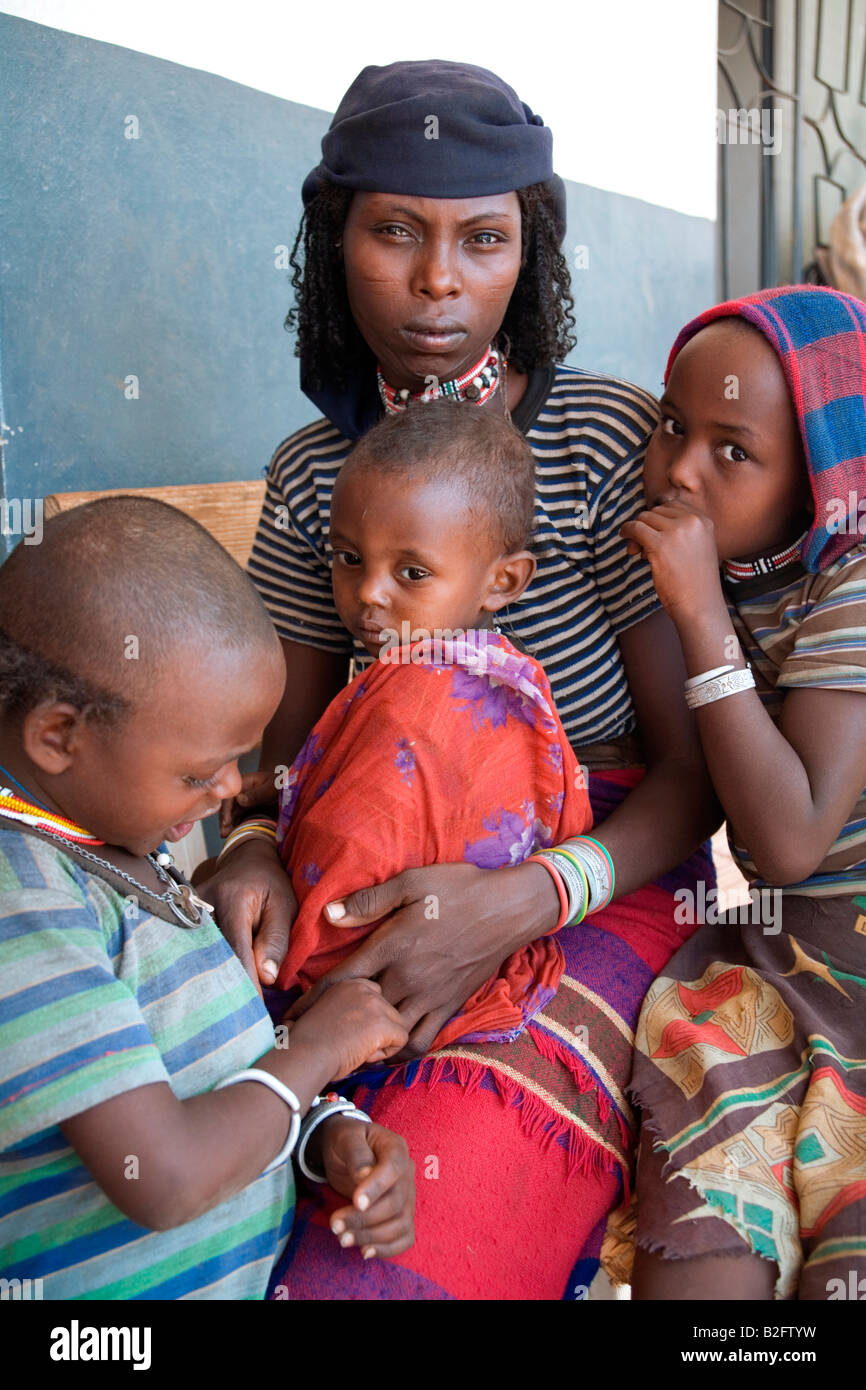 A mother and her three children sit outside a rural government health ...
