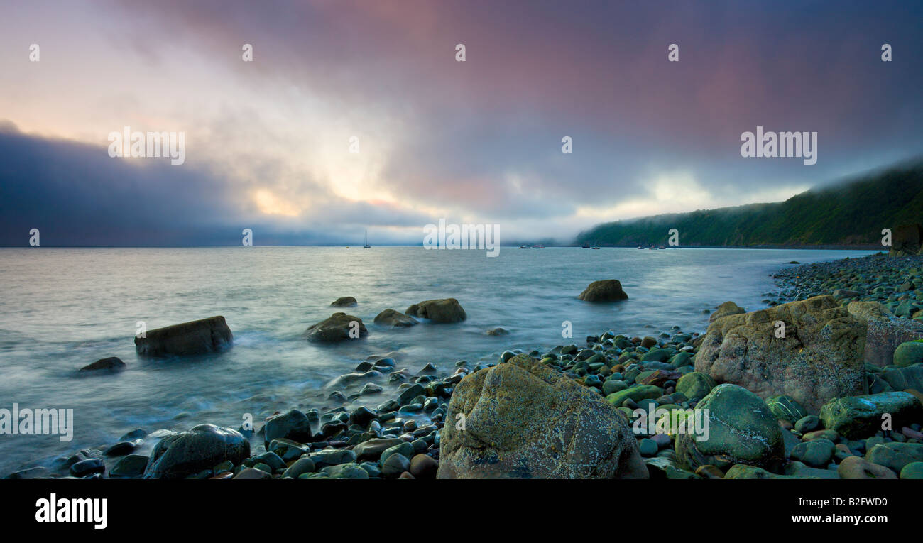 Clearing sea fog tinged pink by the colours of dawn Clovelly Devon ...