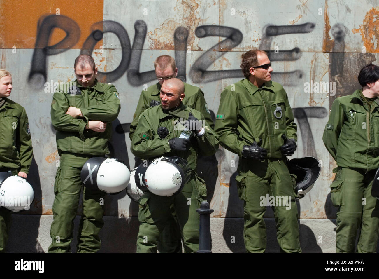 A group of German riot police stand in front of a wall spray painted ...