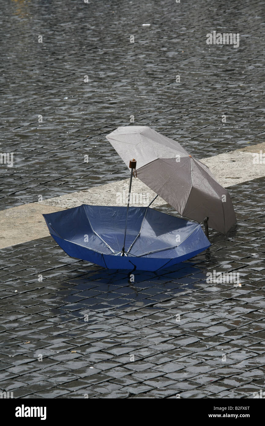 two umbrellas left on pavement in rain in town Stock Photo - Alamy