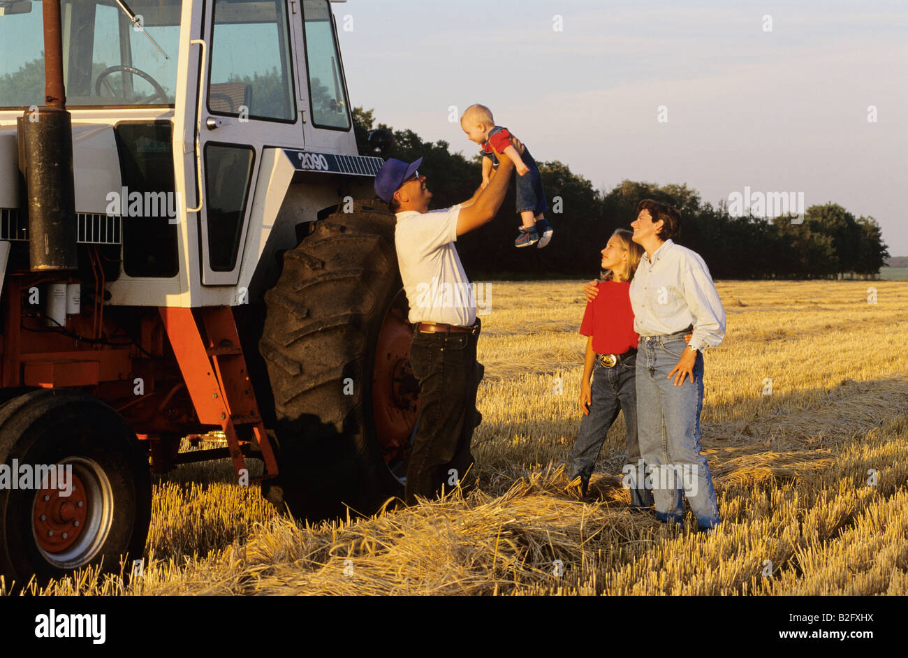 Young Family standing beside a tractor in a field Stock Photo - Alamy
