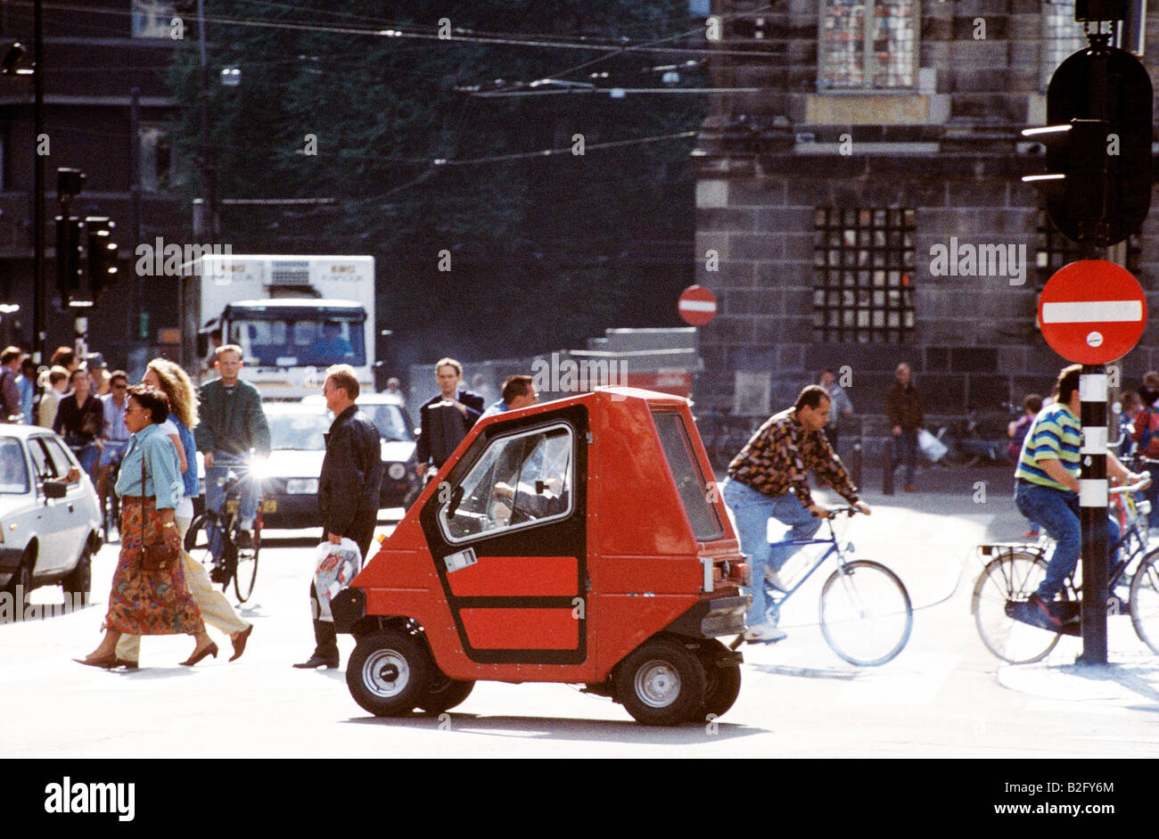 small car driving through central amsterdam past pedestrians and ...