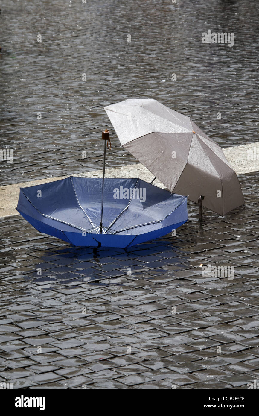 two umbrellas left on pavement in rain in town Stock Photo - Alamy