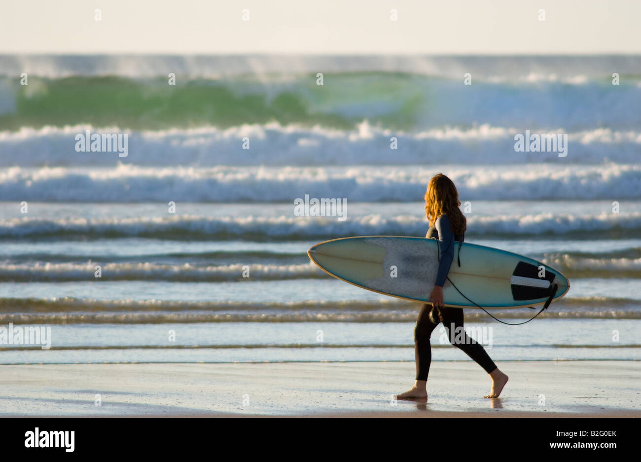 Atmospheric images of surfers walking along surf and beach with ...