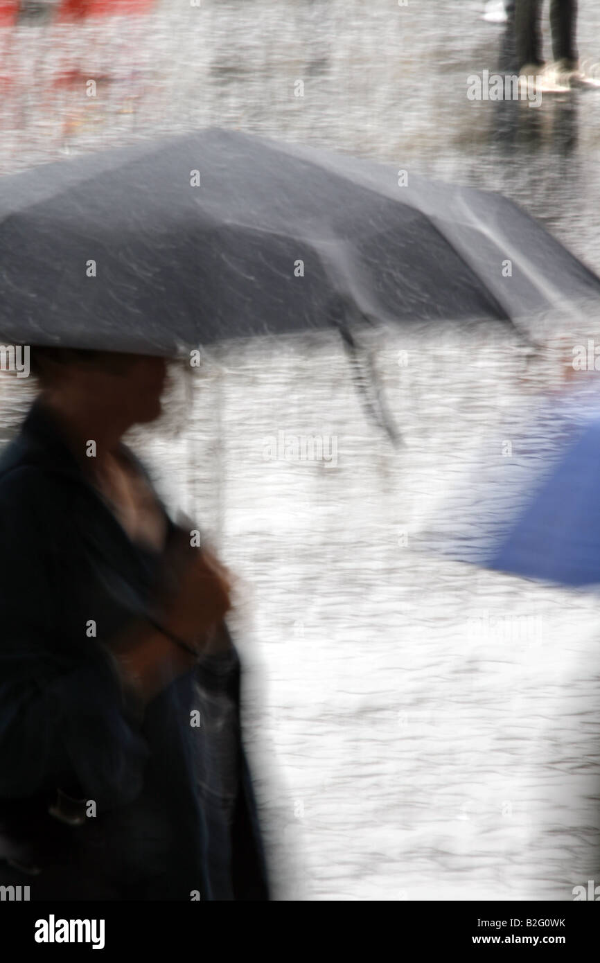 person with umbrella in heavy rain in town Stock Photo - Alamy