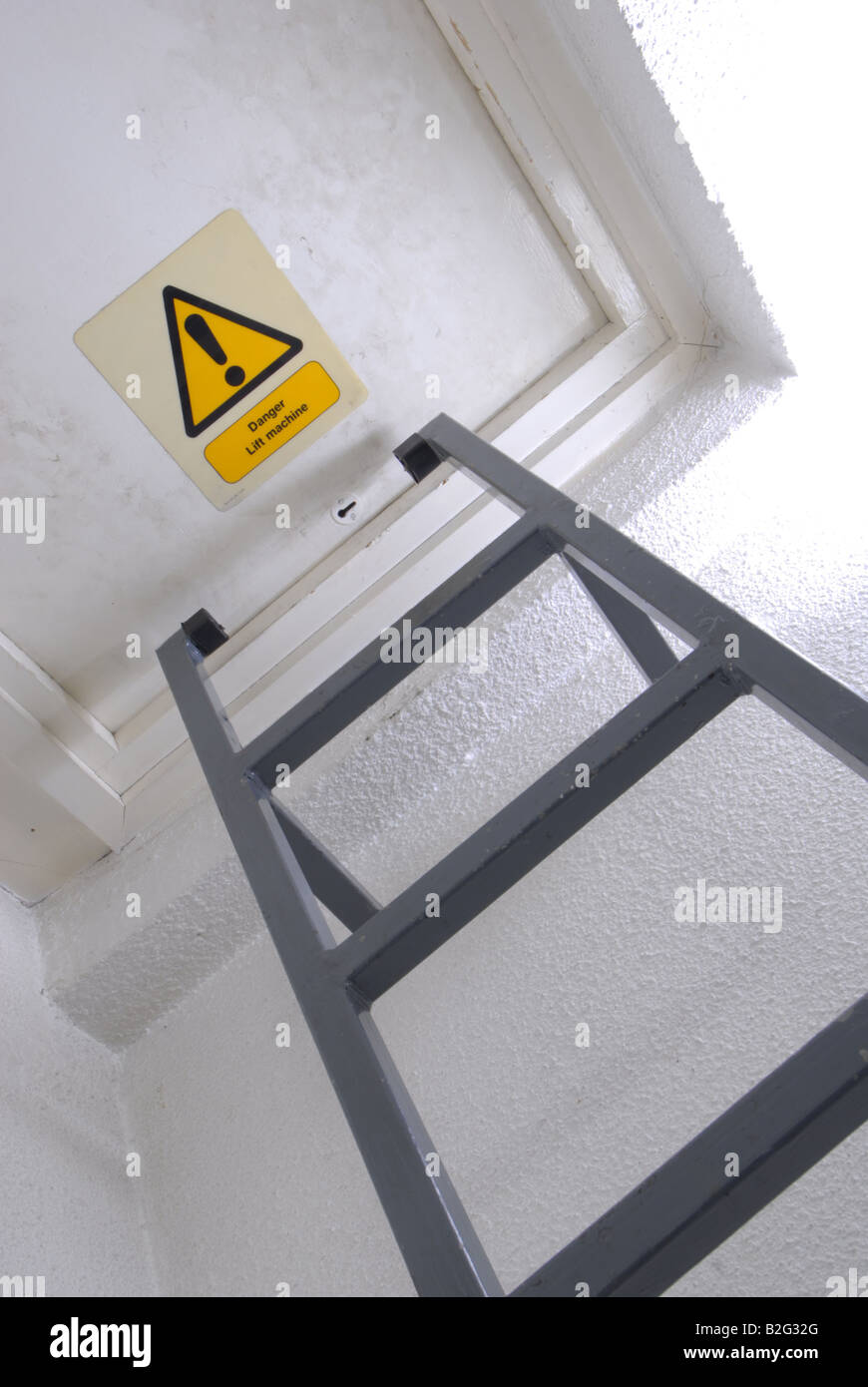 A ladder going up to a loft access with a yellow hazard warning symbol ...