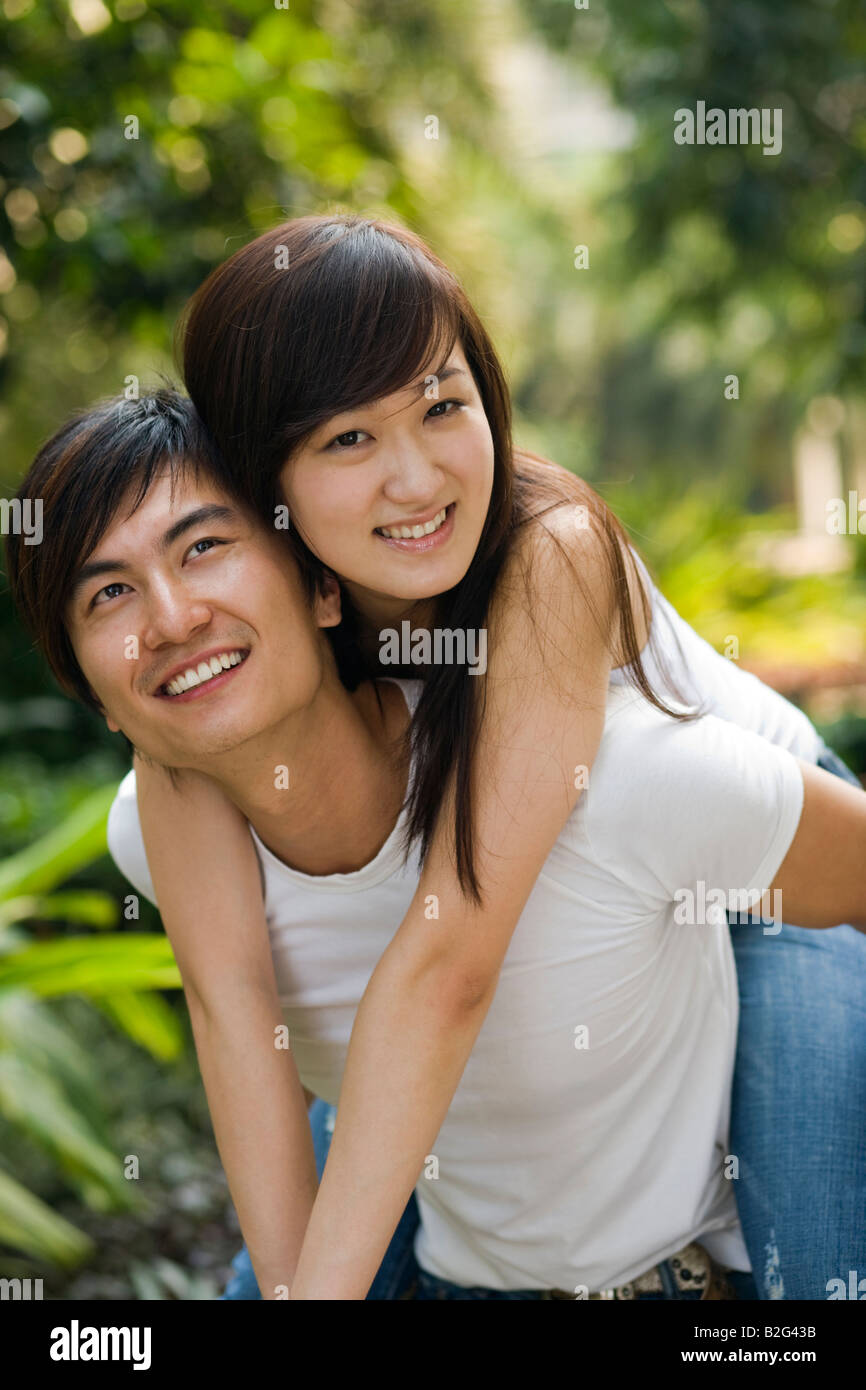 Close-up of a young man riding piggyback on a young man and smiling ...