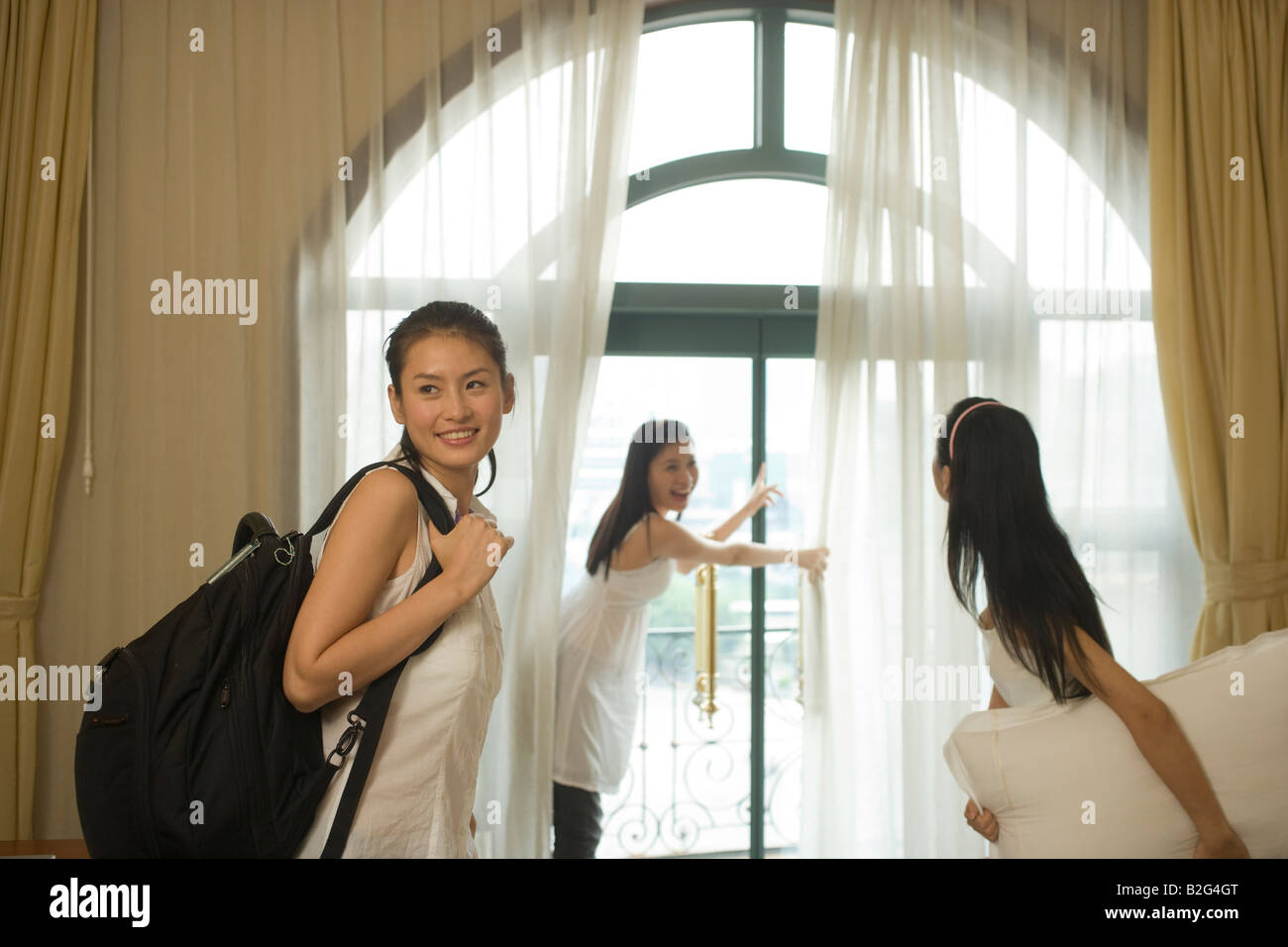 Young woman carrying a backpack with her friends in the background ...