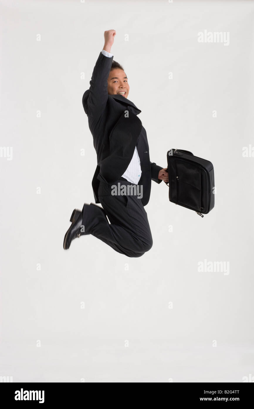 Portrait of a businessman holding a briefcase and jumping Stock Photo ...