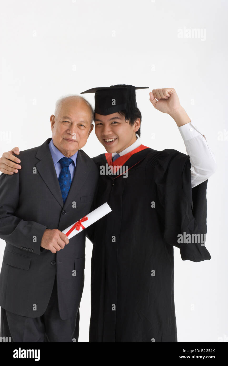 Portrait of a young male graduate standing with his father and smiling ...