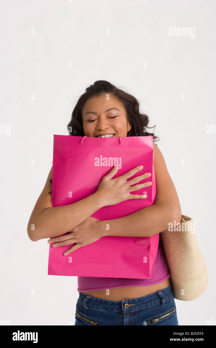 Young woman hugging a shopping bag and smiling Stock Photo - Alamy