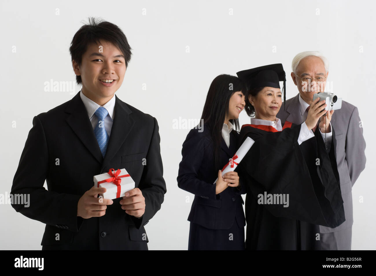 Young man holding a gift with his family looking at a home video camera ...